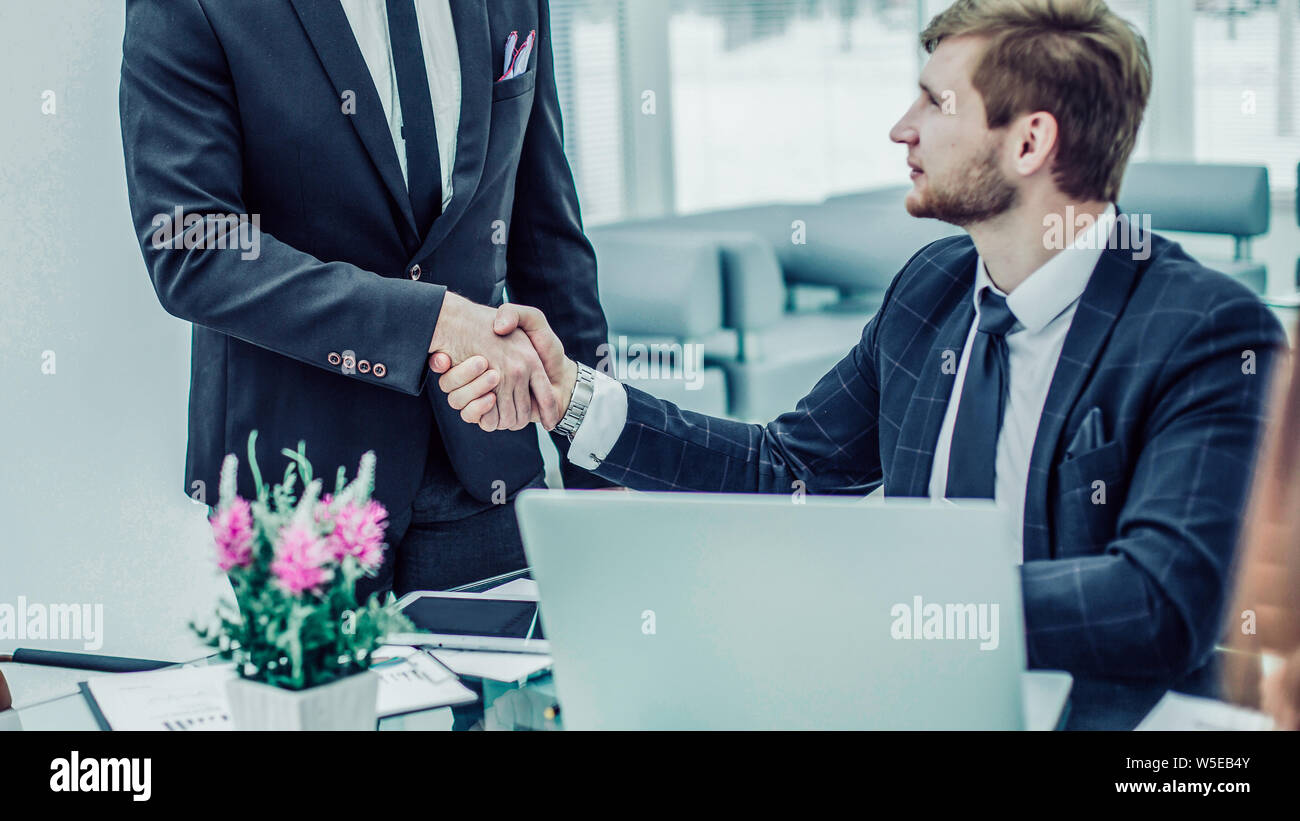 handshake between colleagues in the workplace in a modern office.the ...