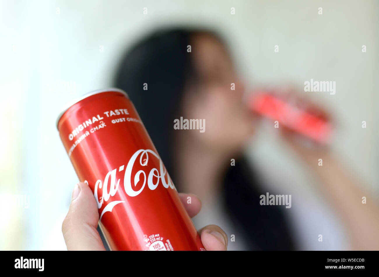 KHARKIV, UKRAINE - JULY 15, 2019: Brunette woman drinks Coca-Cola drink ...