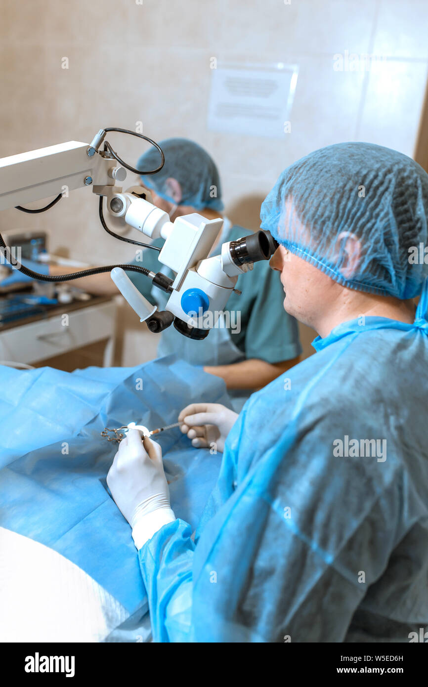 ophthalmologist surgeon looking through surgical microscope doing ...