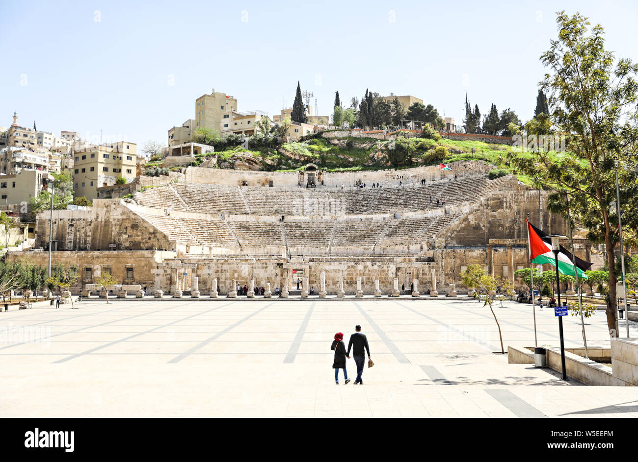 A muslim couple holds hands and walks across the park in front of the ...