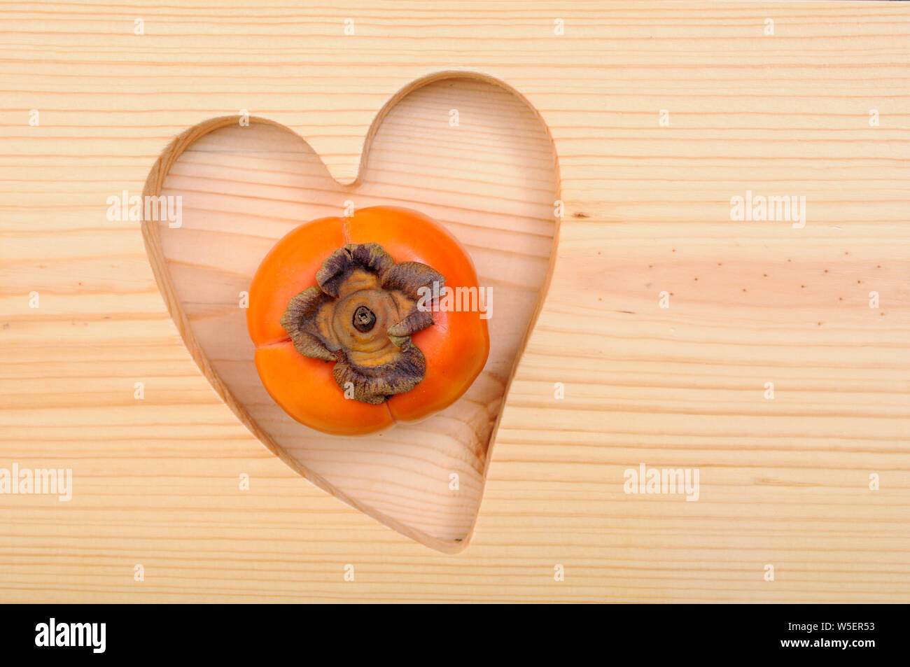 a delicious ripe persimmon in heart shape wooden tray Stock Photo - Alamy