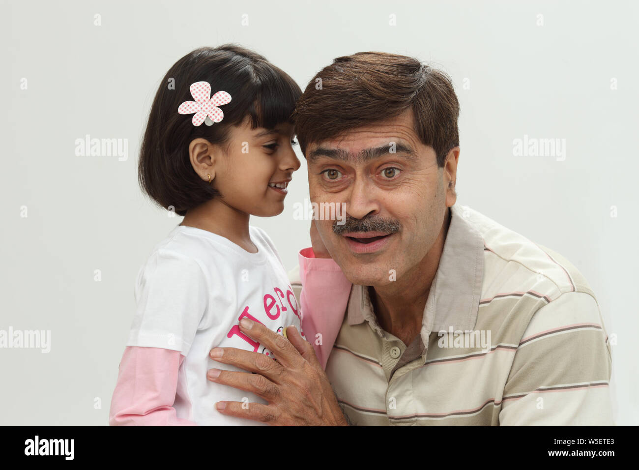 Girl whispering into her grandfather's ear Stock Photo - Alamy
