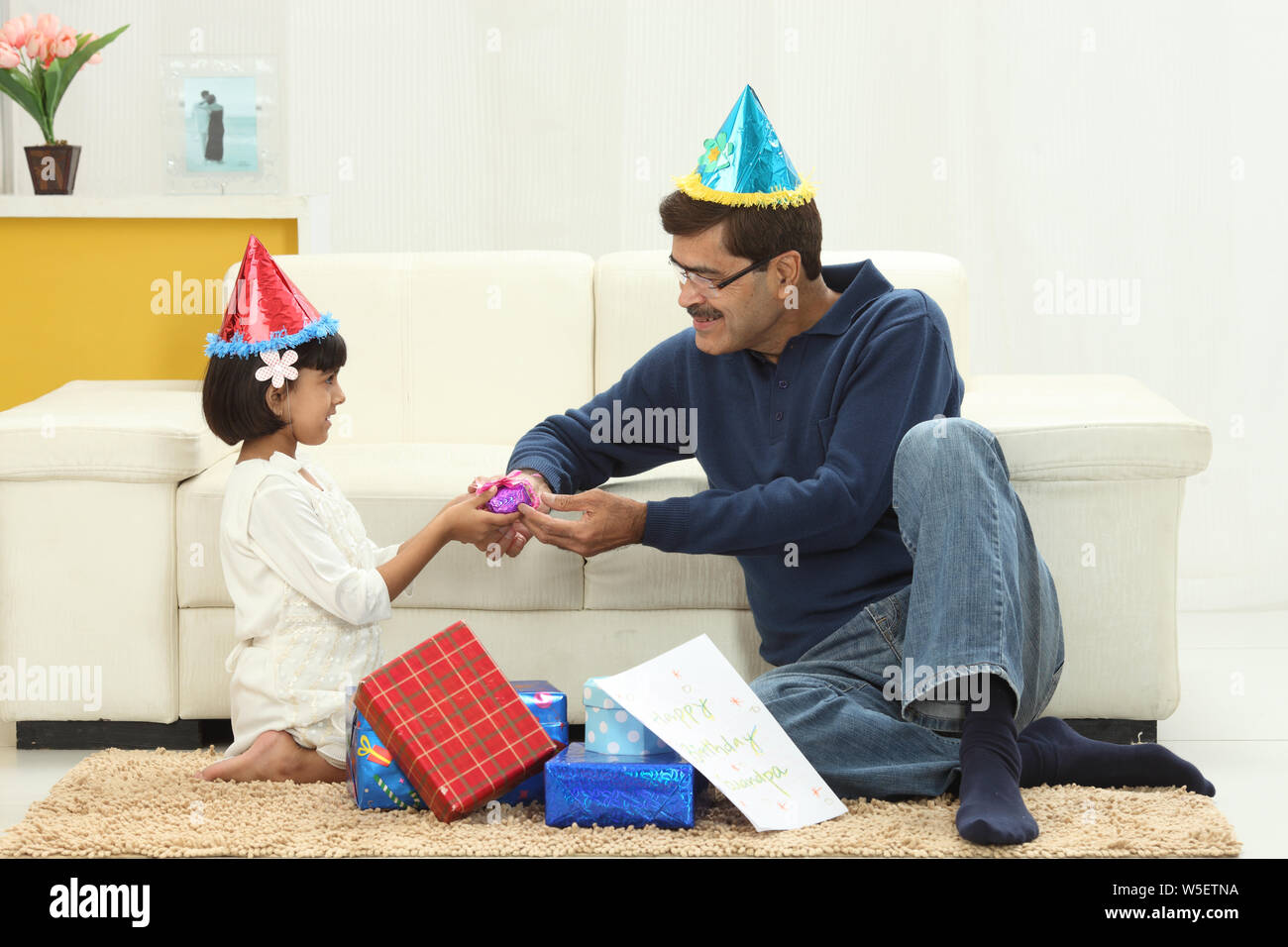 Girl giving gift to his grandfather at home Stock Photo - Alamy