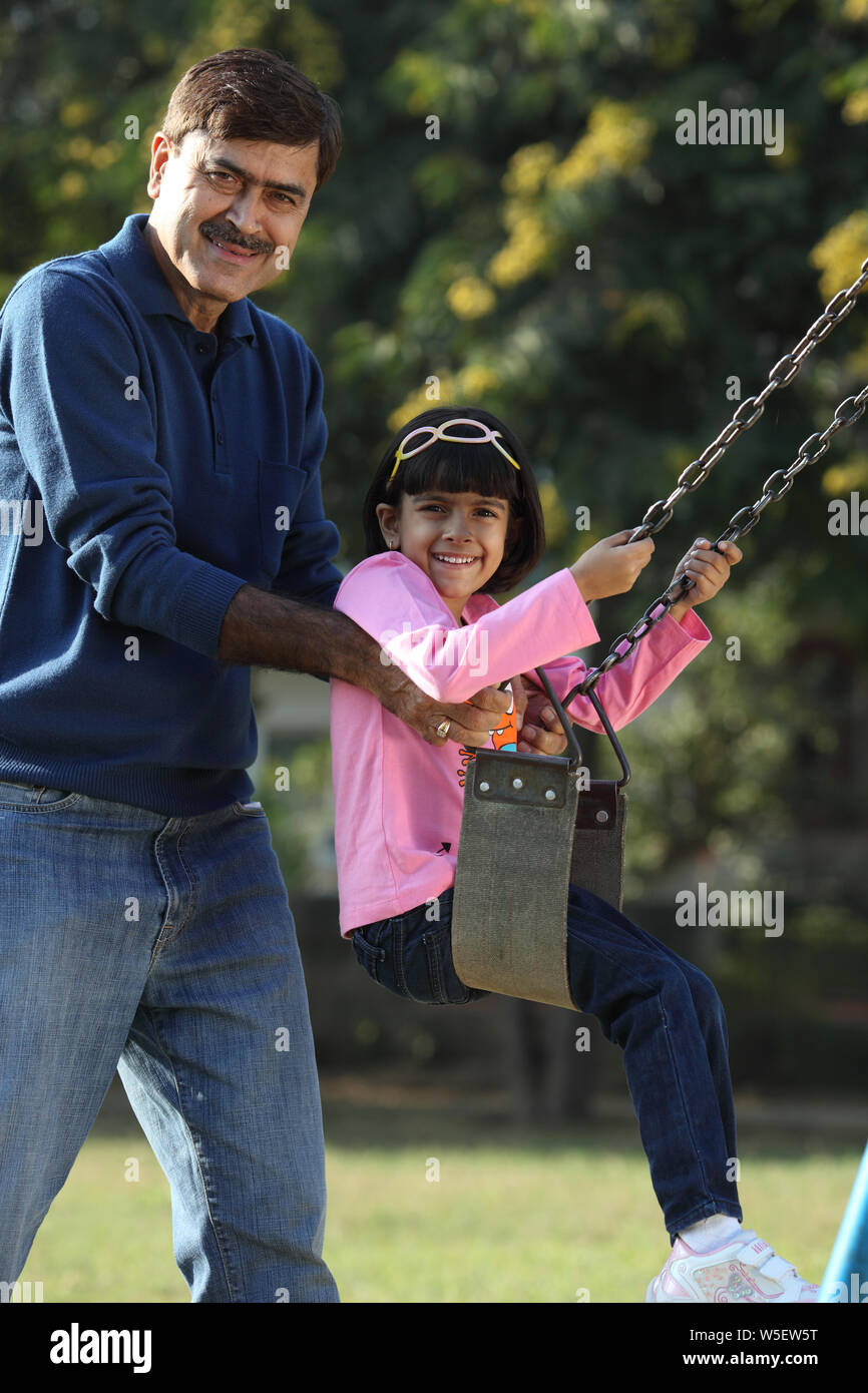 Indian man pushing his granddaughter on the swing Stock Photo - Alamy