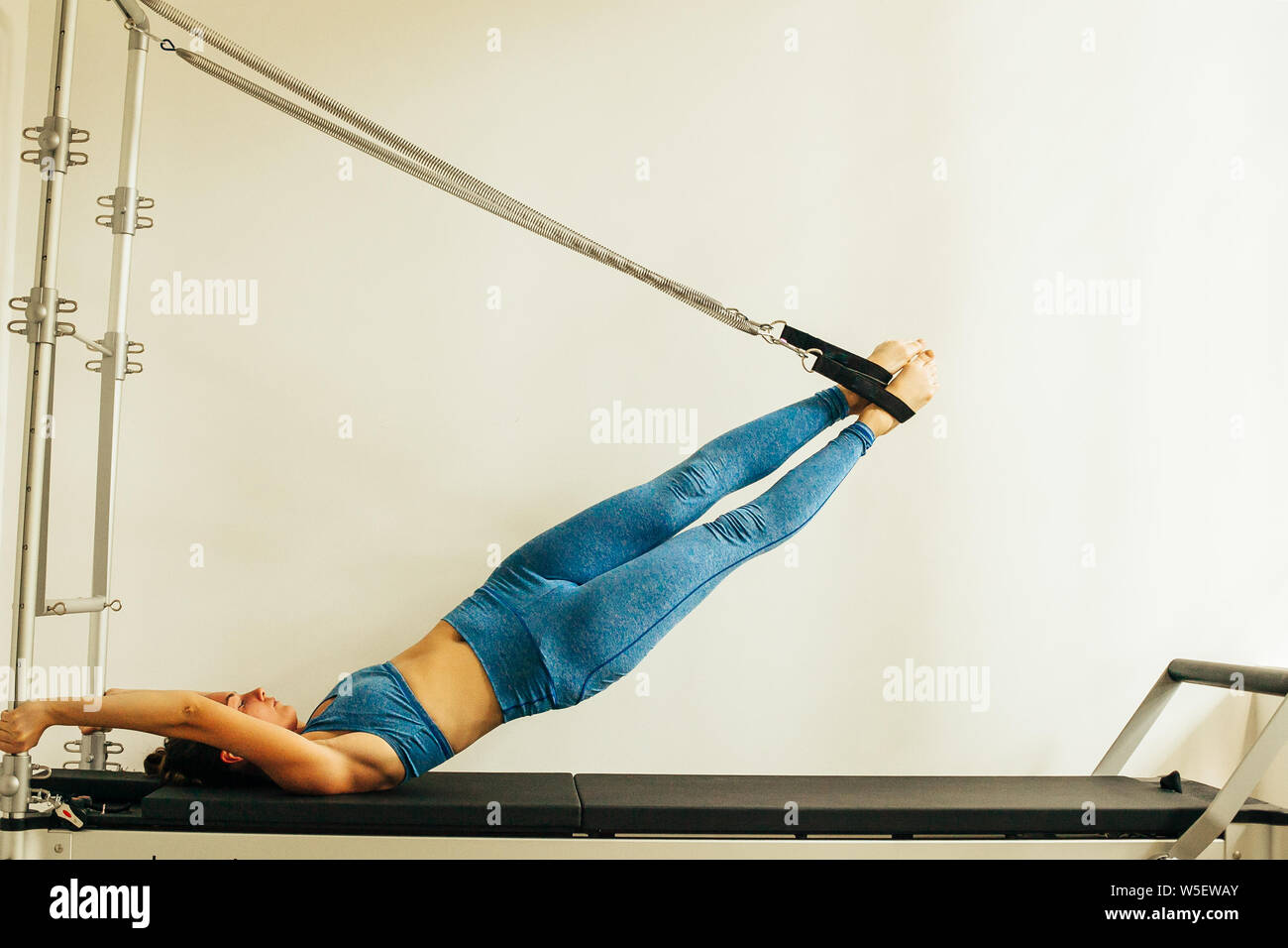 Woman performing Pilates exercise using a Cadillac or Trapeze table ...