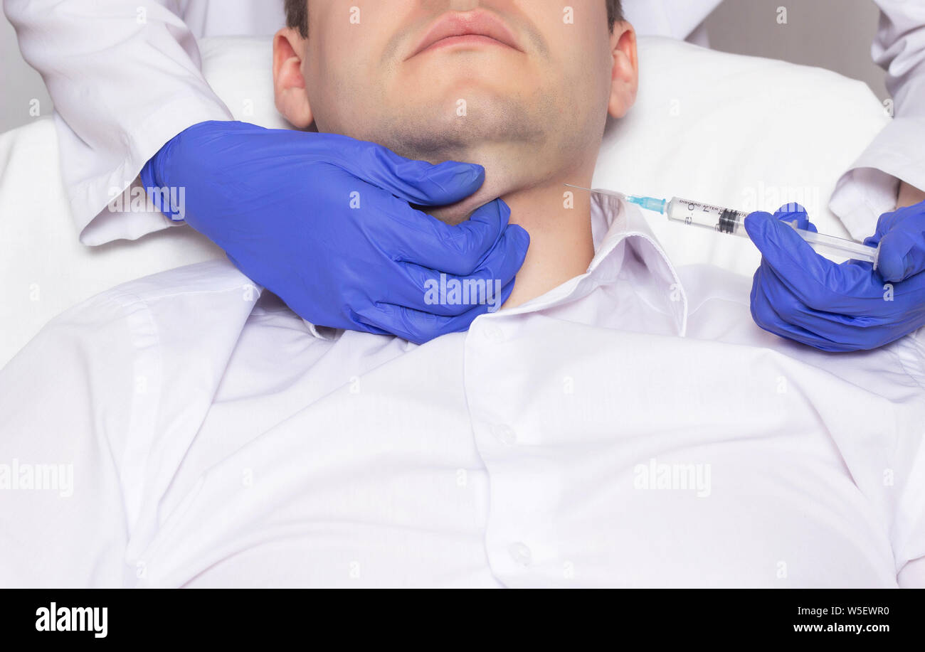 Doctor cosmetologist conducts procedure for a man with a double chin ...