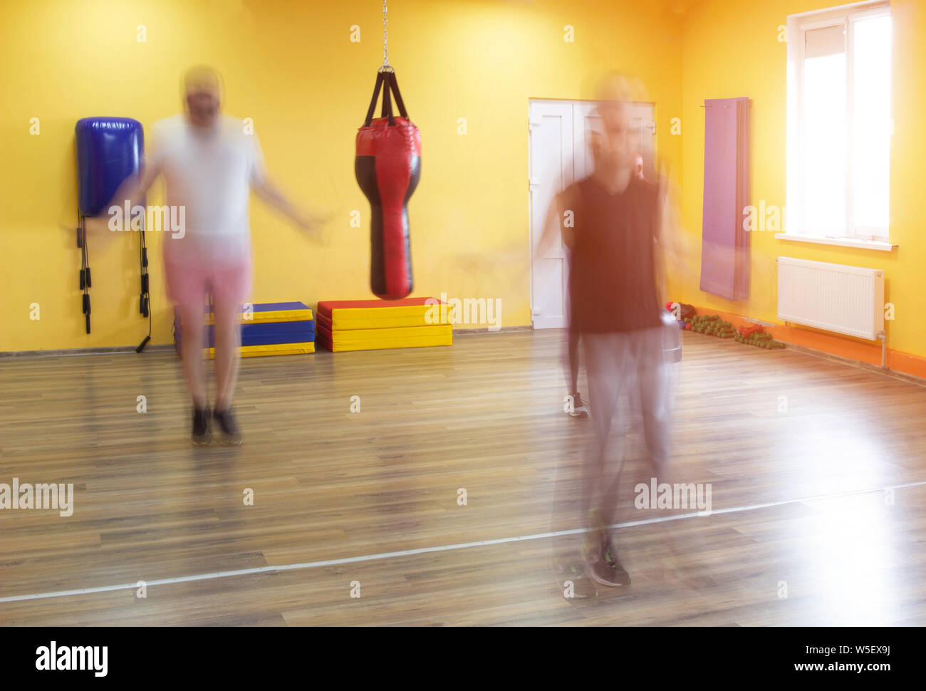 The coach trains a group of men and girls jumping rope in the gym, warm ...