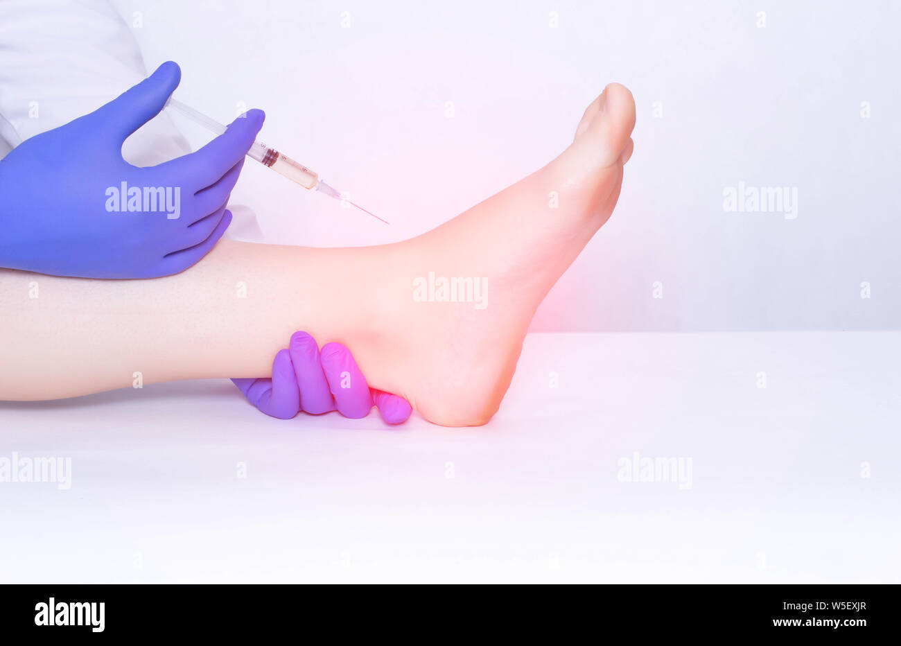 The doctor makes an injection into the ankle joint of the patient in ...