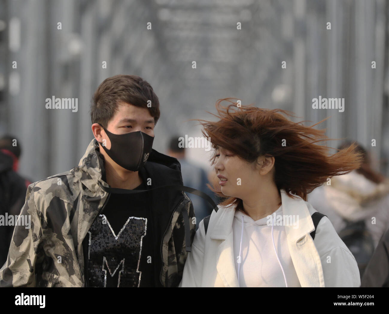 Pedestrians wearing face masks against air pollution walk on a road in ...