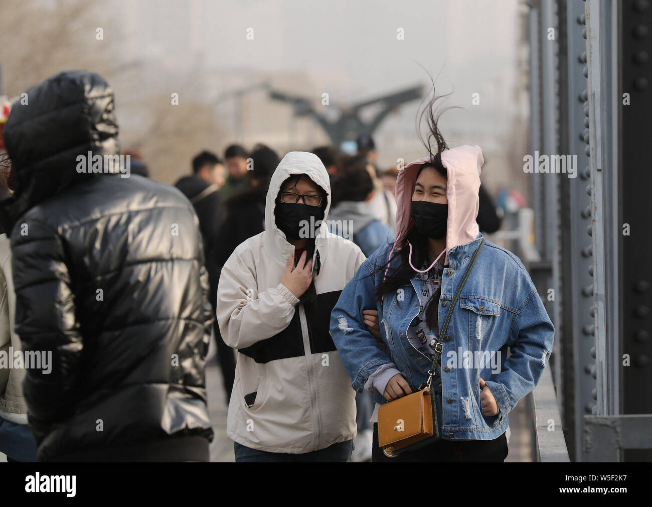Pedestrians wearing face masks against air pollution walk on a road in ...