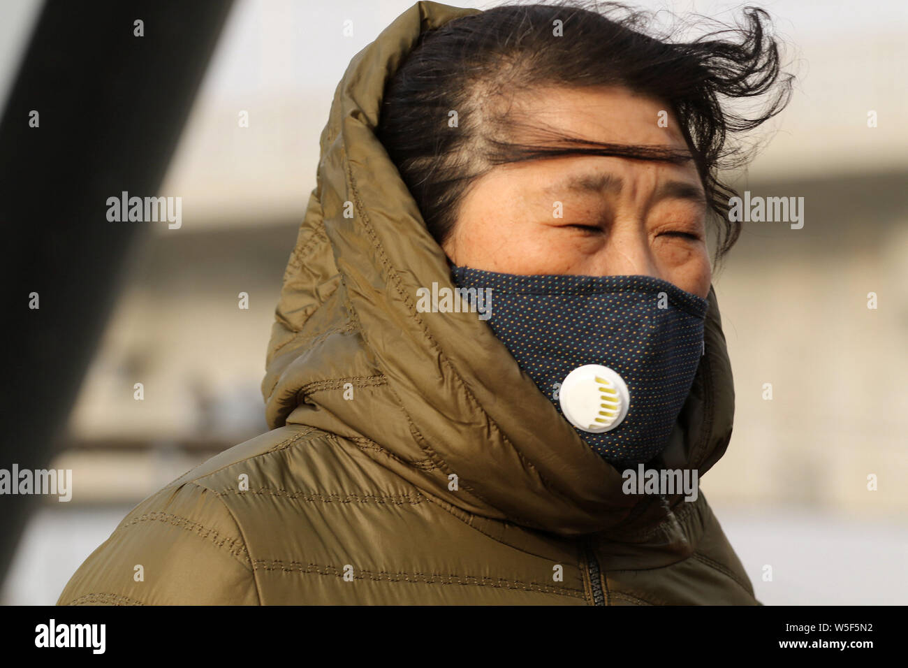 A pedestrian wearing face mask against air pollution walks on a road in ...