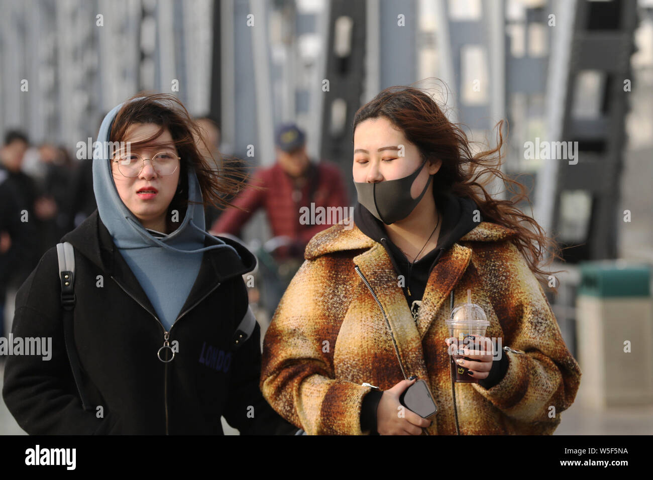 Pedestrians wearing face masks against air pollution walk on a road in ...