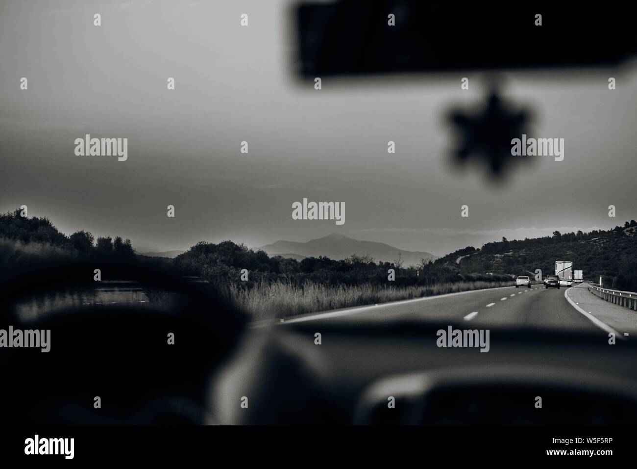 Black and white shot of a drive-through road taken from inside of a car ...