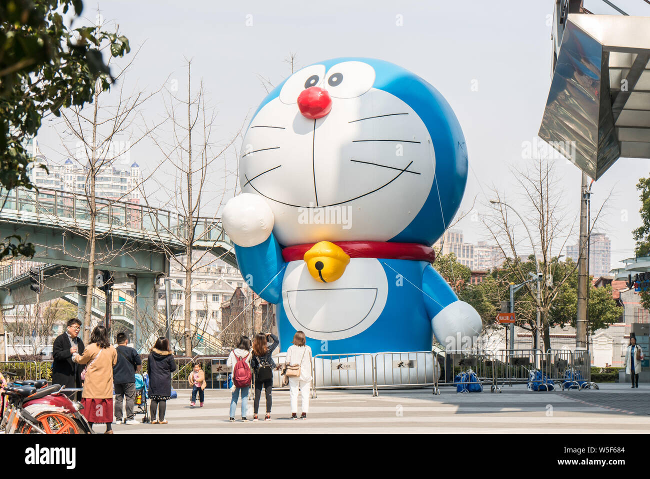 Customers pose for photos with a 10-meter-tall inflated doll featuring ...