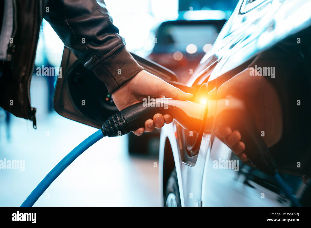 Human hand is holding Electric Car Charging connect to Electric car ...