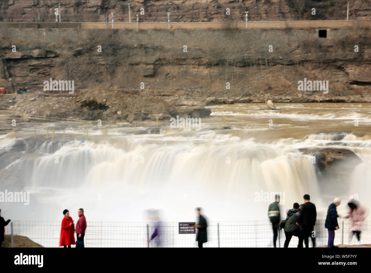 Tourists visit the roaring Hukou Waterfall on the Yellow River as ...