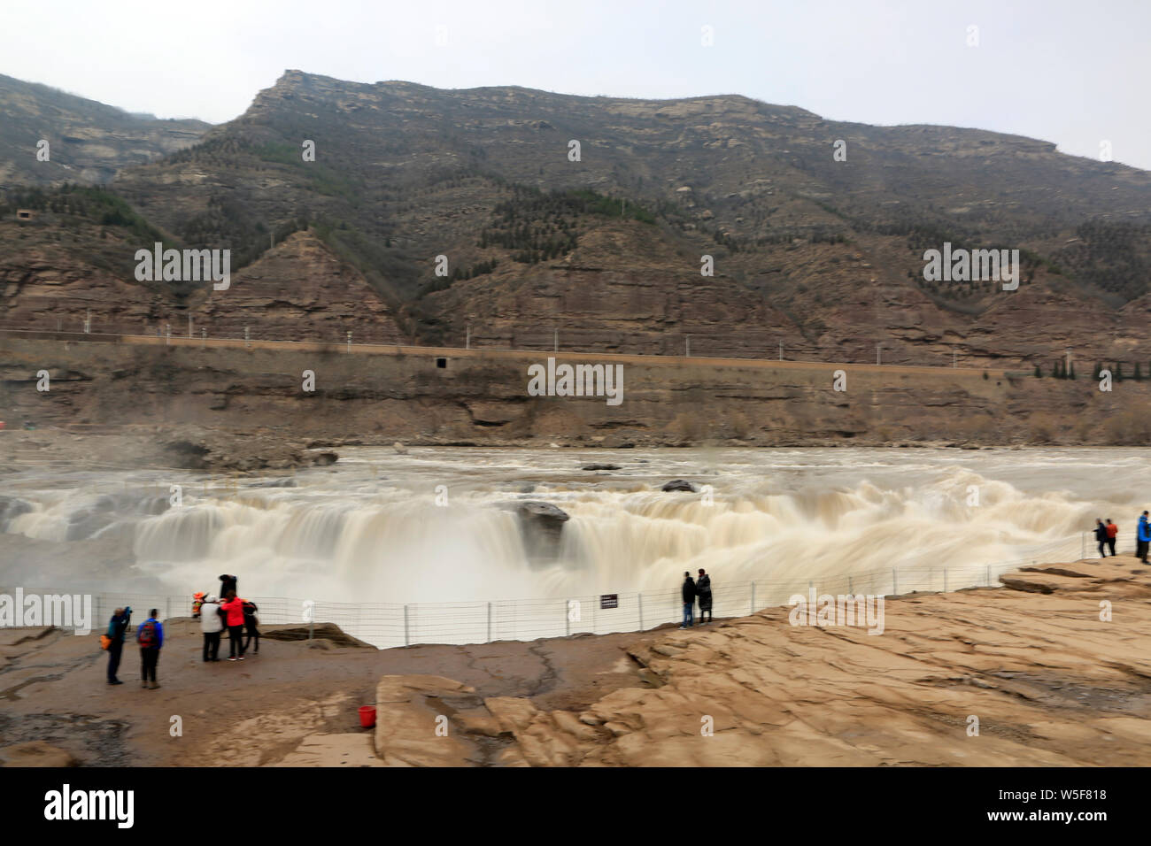 Tourists visit the roaring Hukou Waterfall on the Yellow River as ...