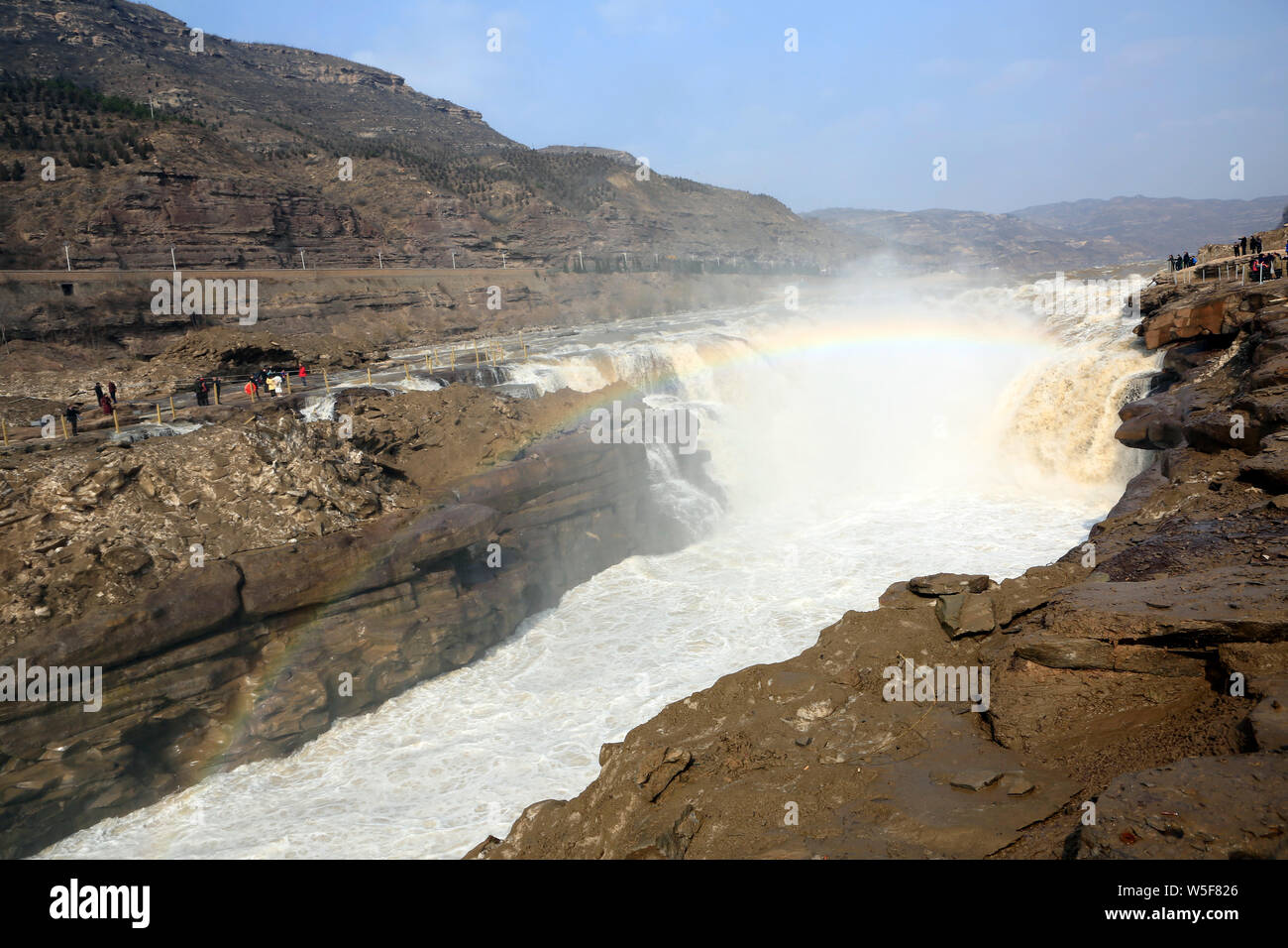 Tourists visit the roaring Hukou Waterfall on the Yellow River as ...