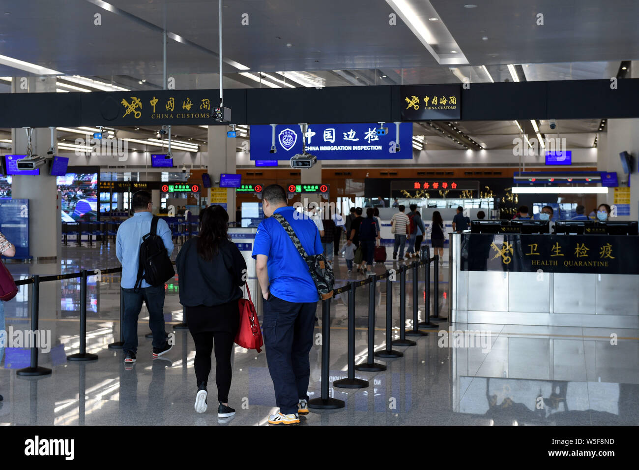--FILE--Tourists queue up to get cleared at a immigration inspection ...