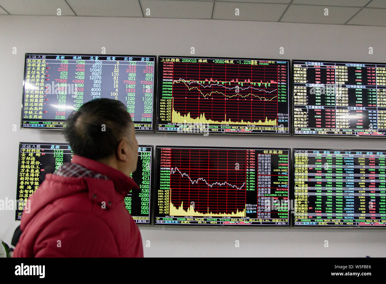 A concerned Chinese investor looks at a screen displaying stock index ...