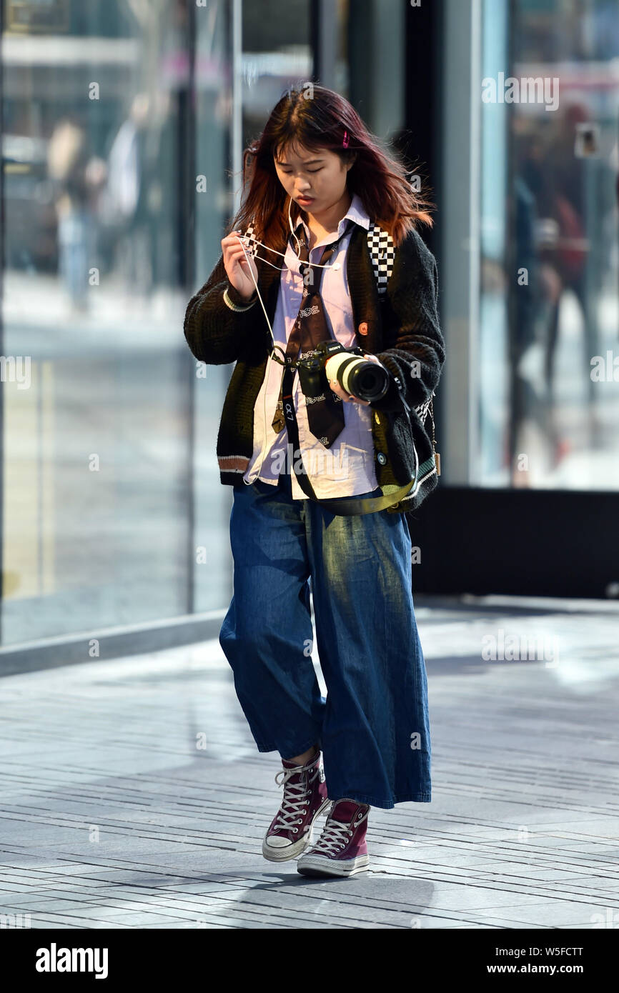 A trendy young Chinese woman walks on the street in Sanlitun, Beijing ...