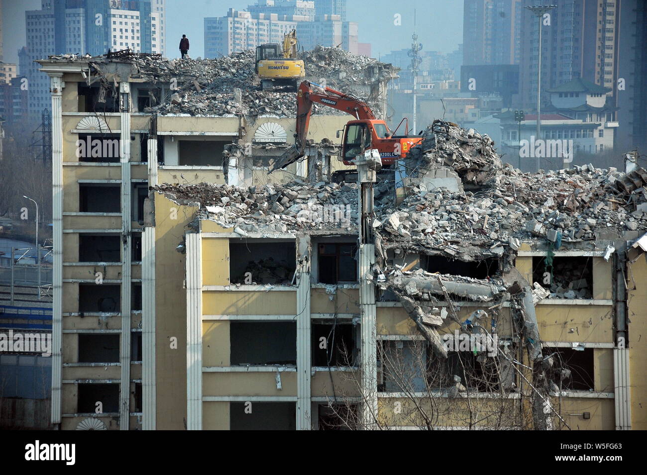 Chinese workers operate the excavators to demolish a residential ...