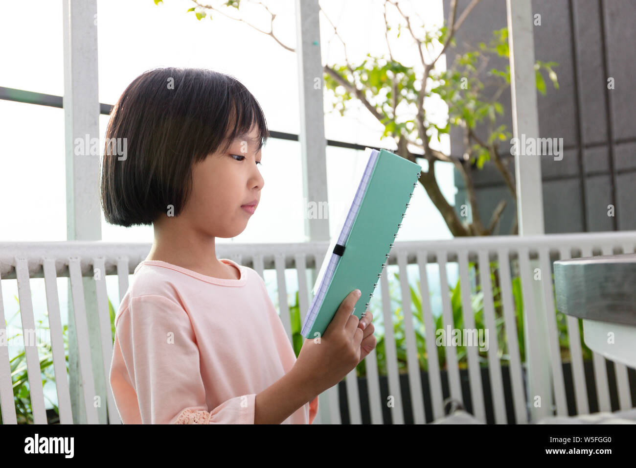 Asian Little Chinese Girl reading book in the outdoor cafe Stock Photo ...