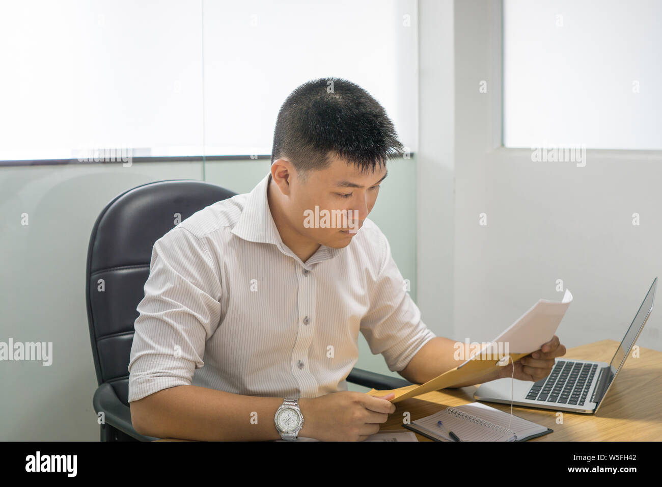 Asian businessman reading financial document in the office Stock Photo ...
