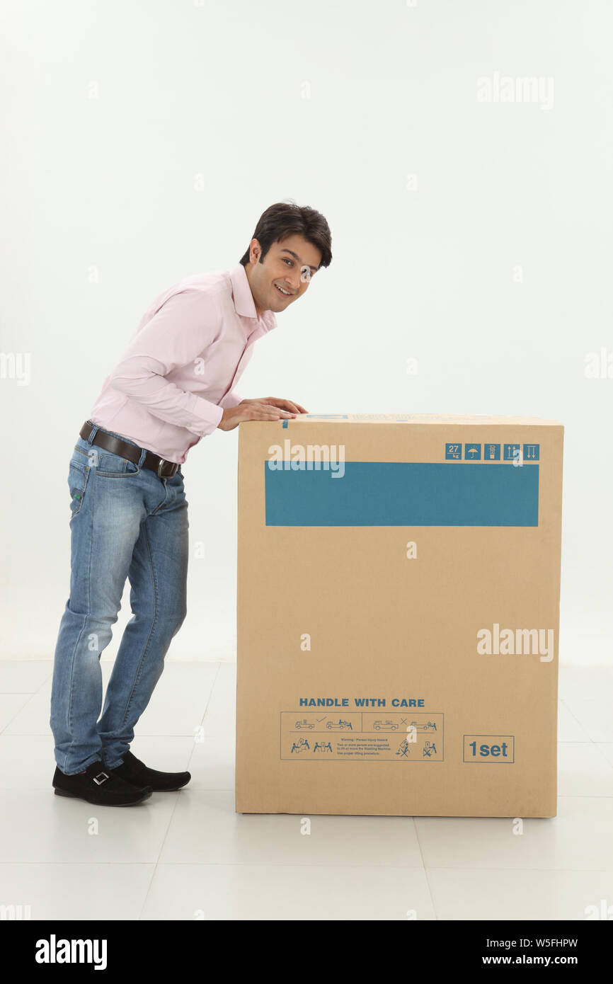 Delivery man pushing a cardboard box and smiling Stock Photo - Alamy