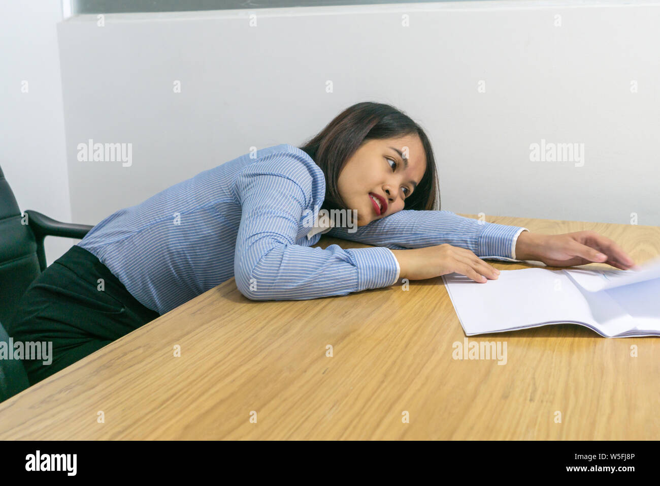 Tired office lady laid down on desk with paperwork in hand Stock Photo ...