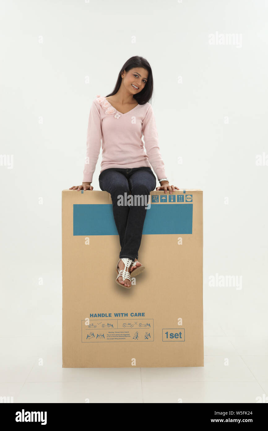 Woman sitting on cardboard box and smiling Stock Photo - Alamy