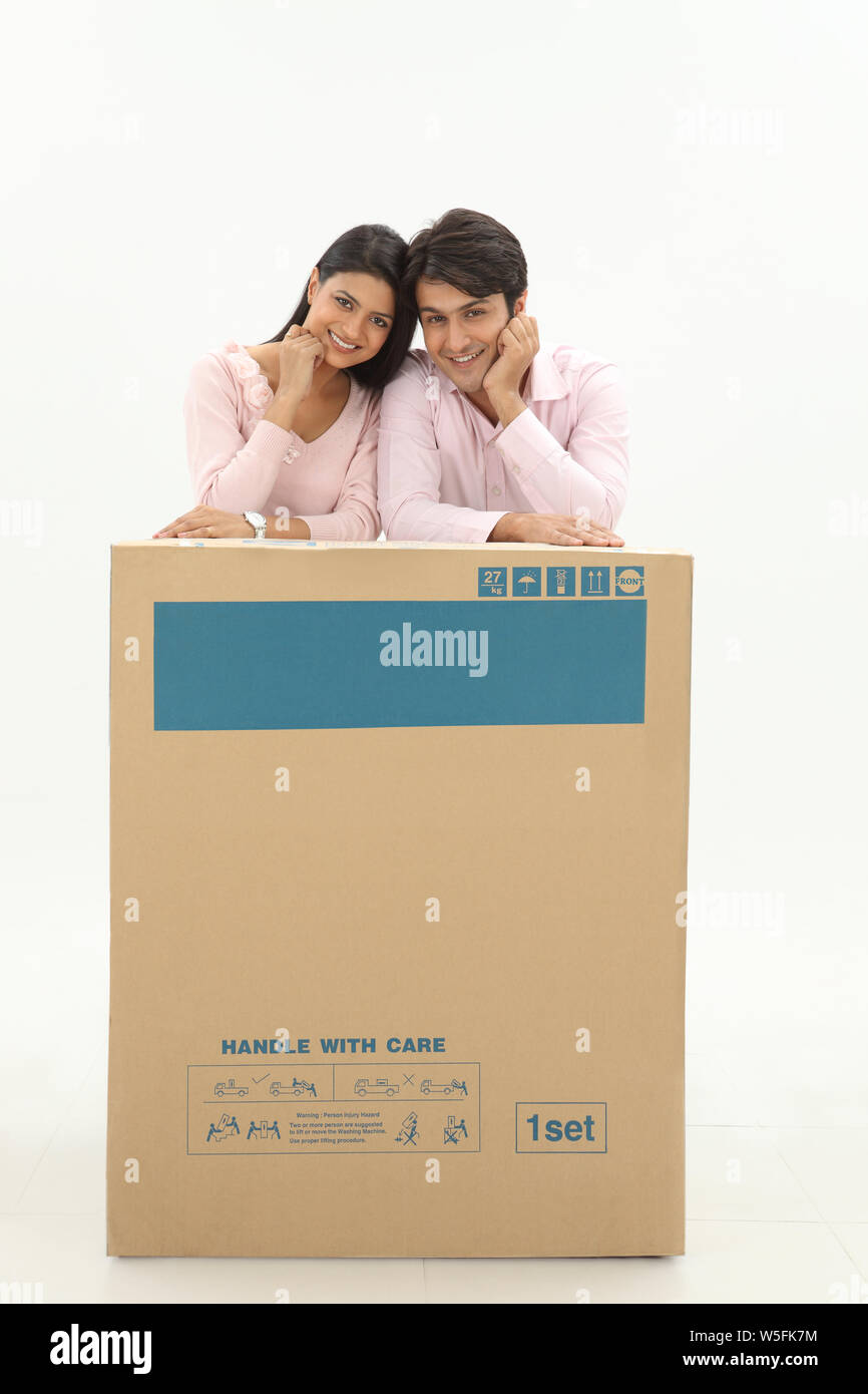 Couple leaning over a cardboard box and smiling Stock Photo - Alamy