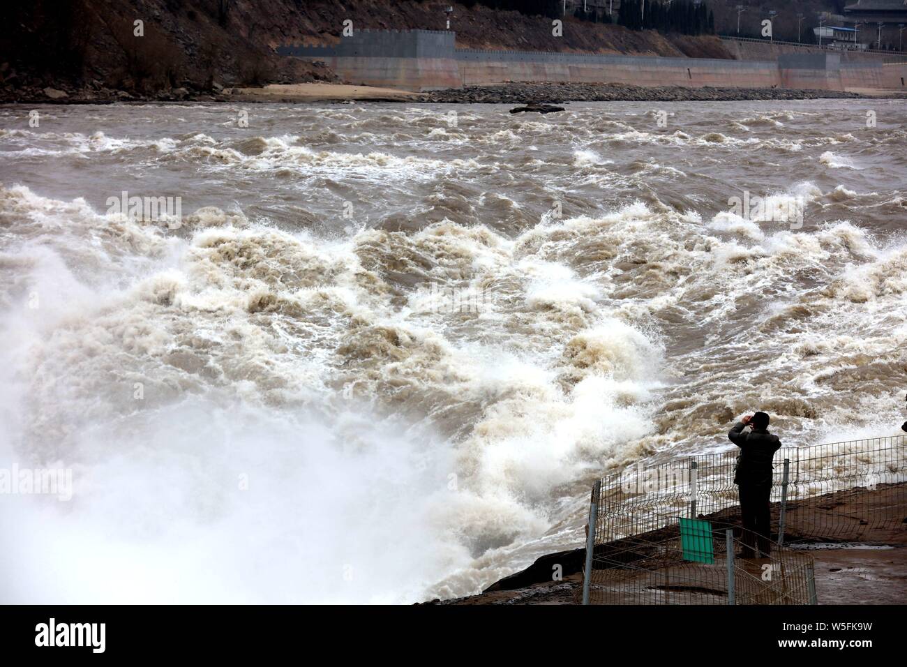 Tourists visit the roaring Hukou Waterfall on the Yellow River as ...