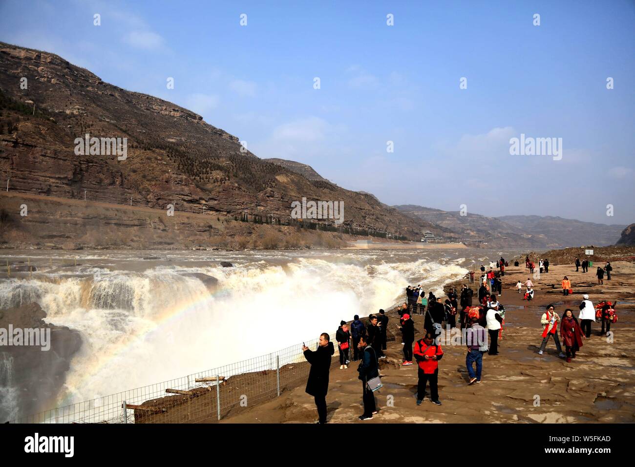 Tourists visit the roaring Hukou Waterfall on the Yellow River as ...