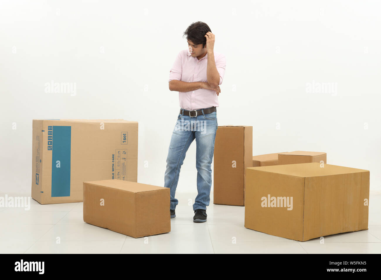 Man standing with cardboard boxes and scratching heads Stock Photo - Alamy