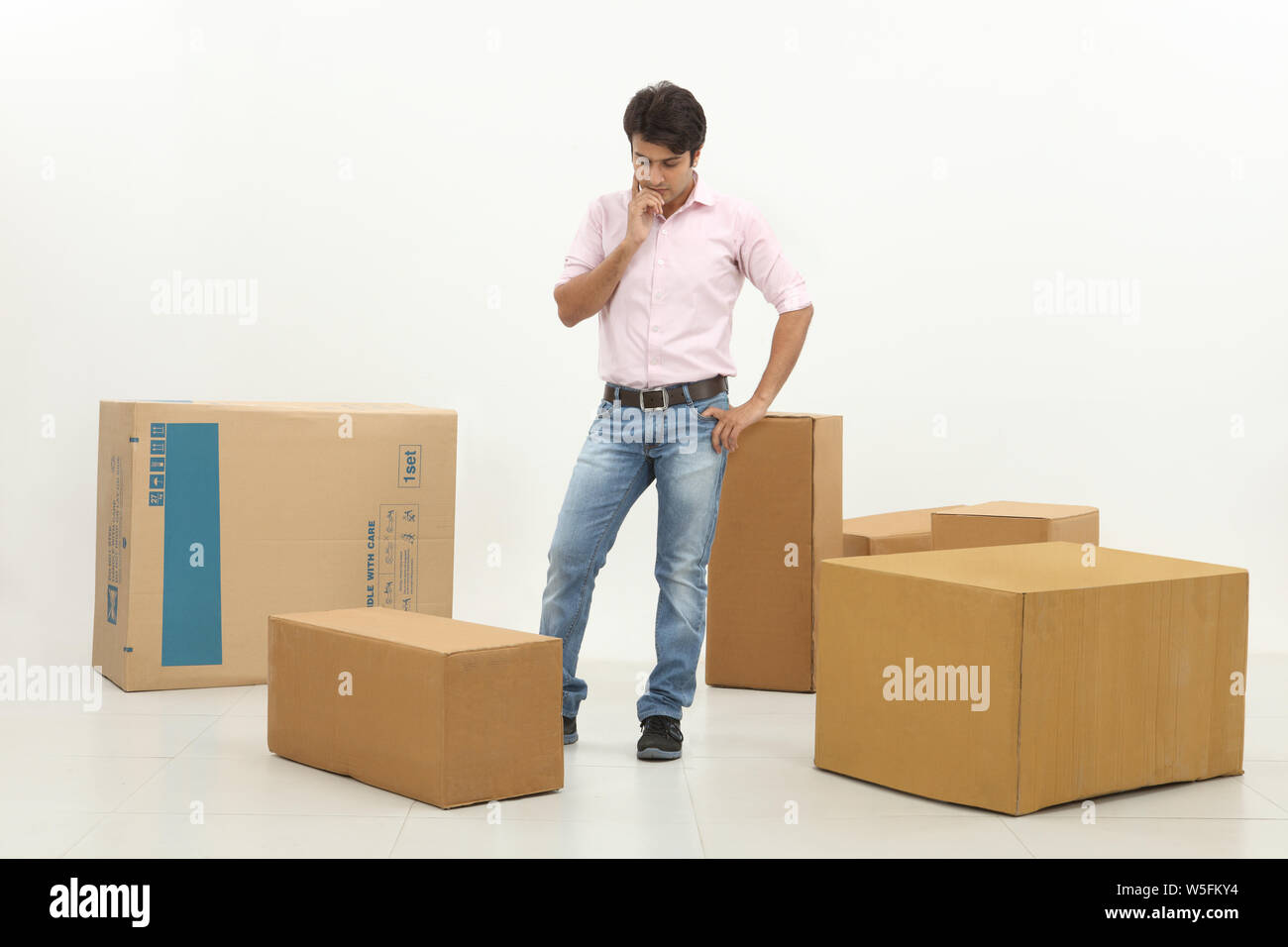 Man standing with cardboard boxes thinking Stock Photo - Alamy