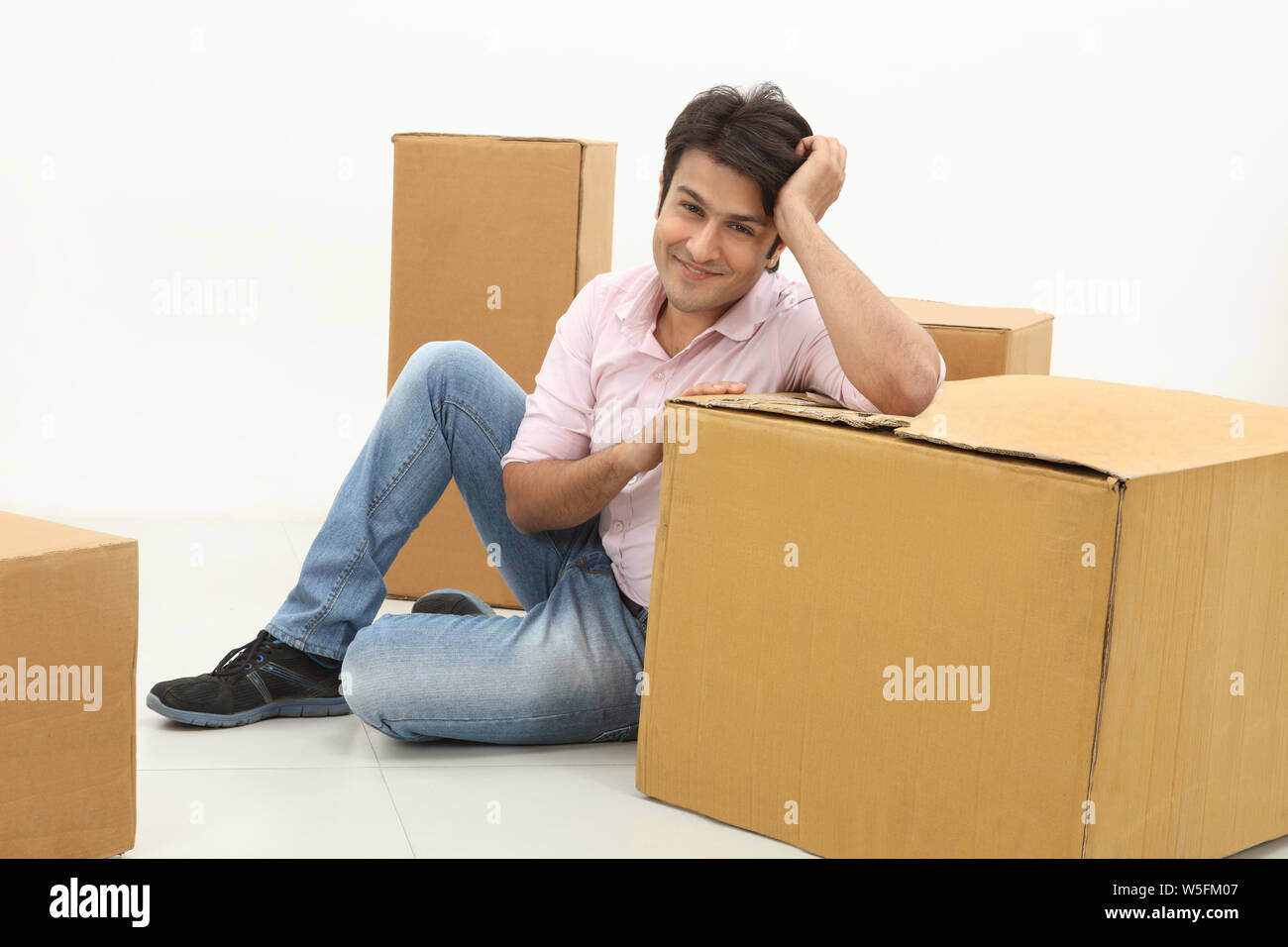Man sitting with cardboard boxes smiling Stock Photo - Alamy