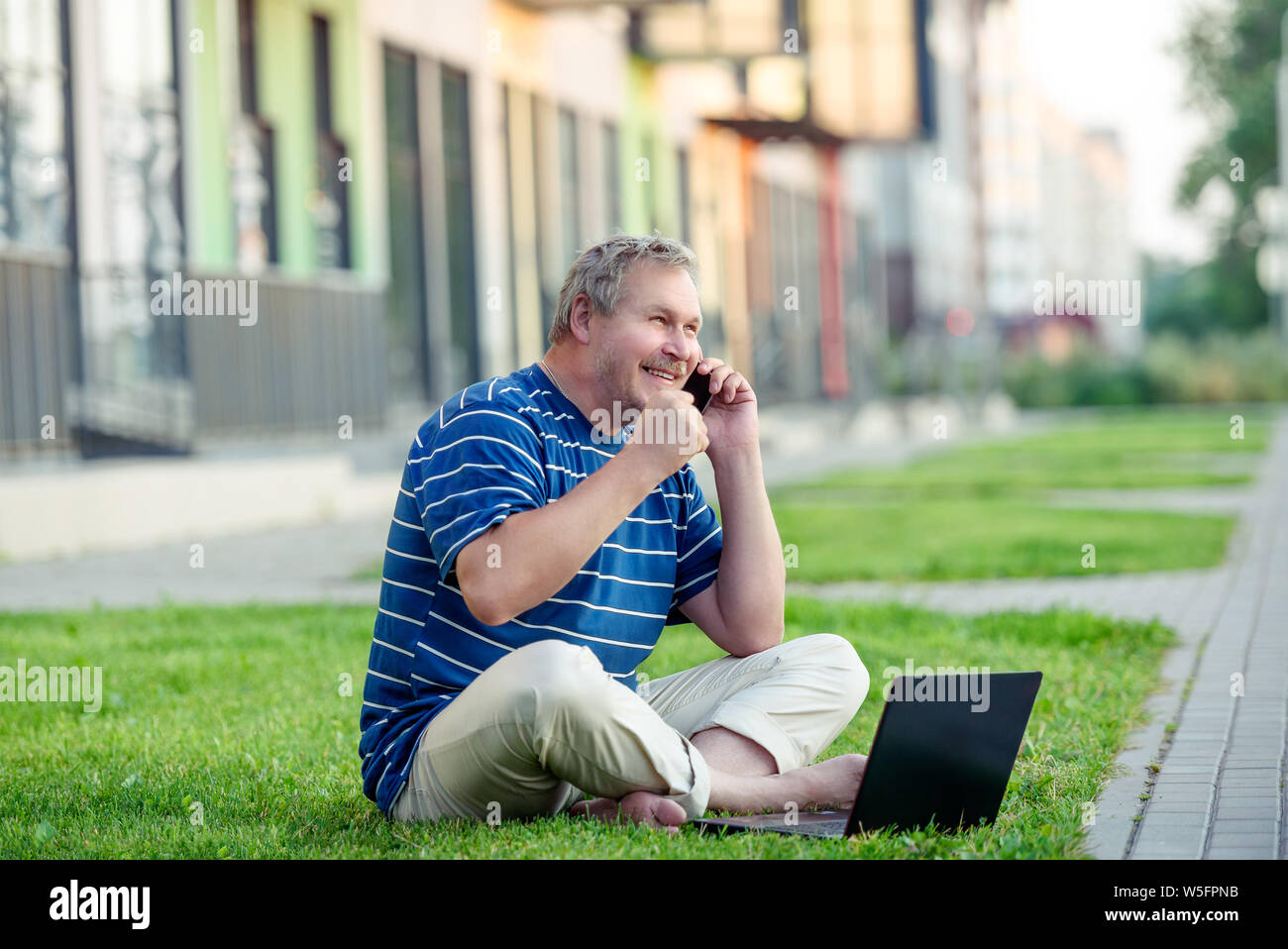 A handsome man on the lawn with a laptop excitedly watching content ...