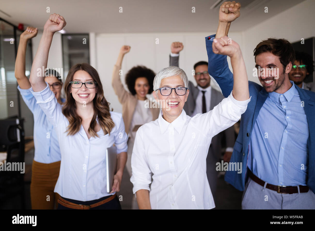 Happy business people celebrating success at company Stock Photo - Alamy