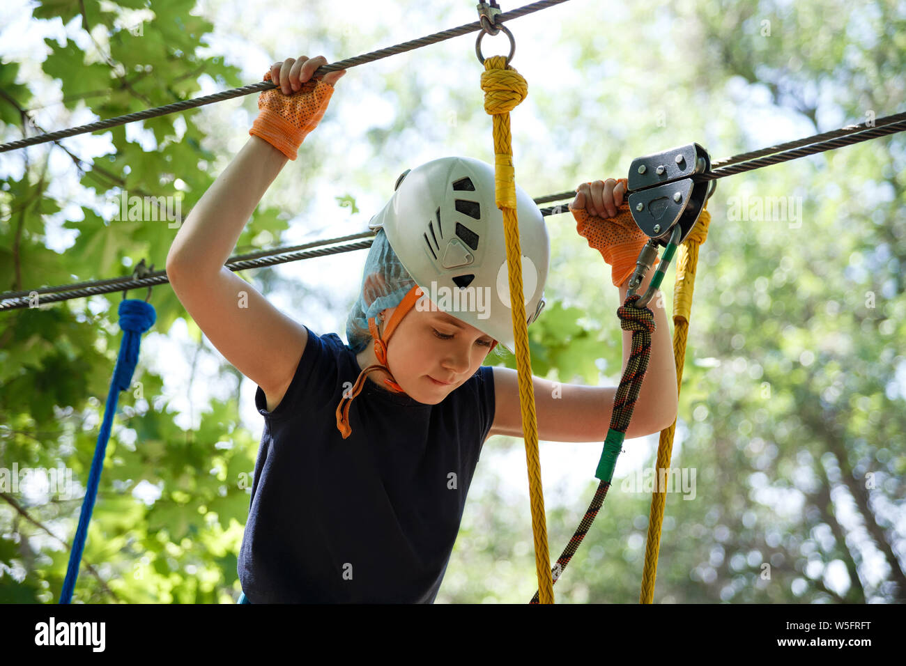 8 years old girl in forest adventure park. Child climb on high rope ...