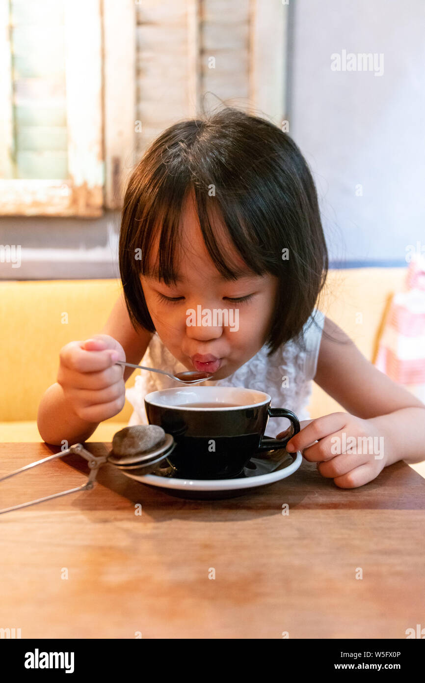 Asian Little Chinese Girl drinking hot tea at an indoor cafe Stock ...