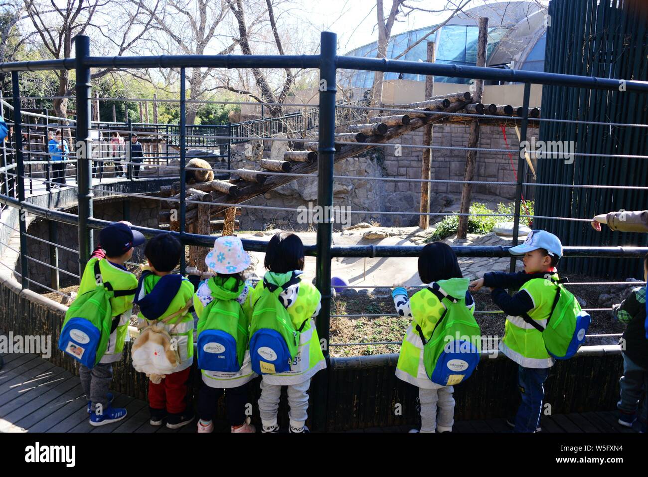 Children dressed in green costumes, under the lead of a teacher, walk ...