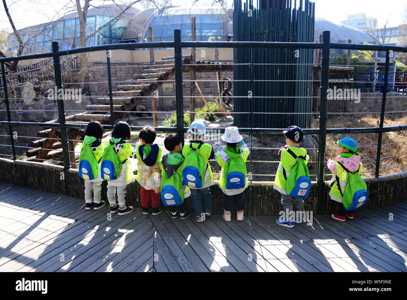 Children dressed in green costumes, under the lead of a teacher, walk ...