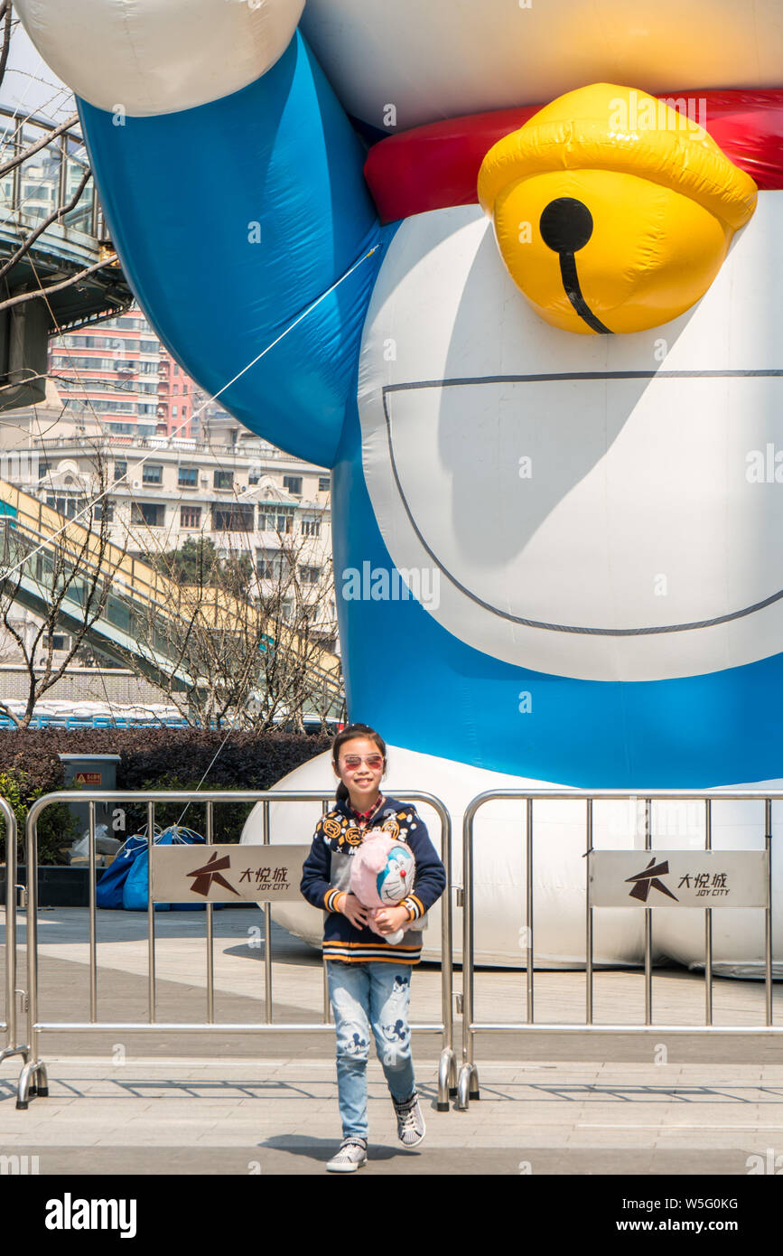 A kid poses for photos with a 10-meter-tall inflated doll featuring ...