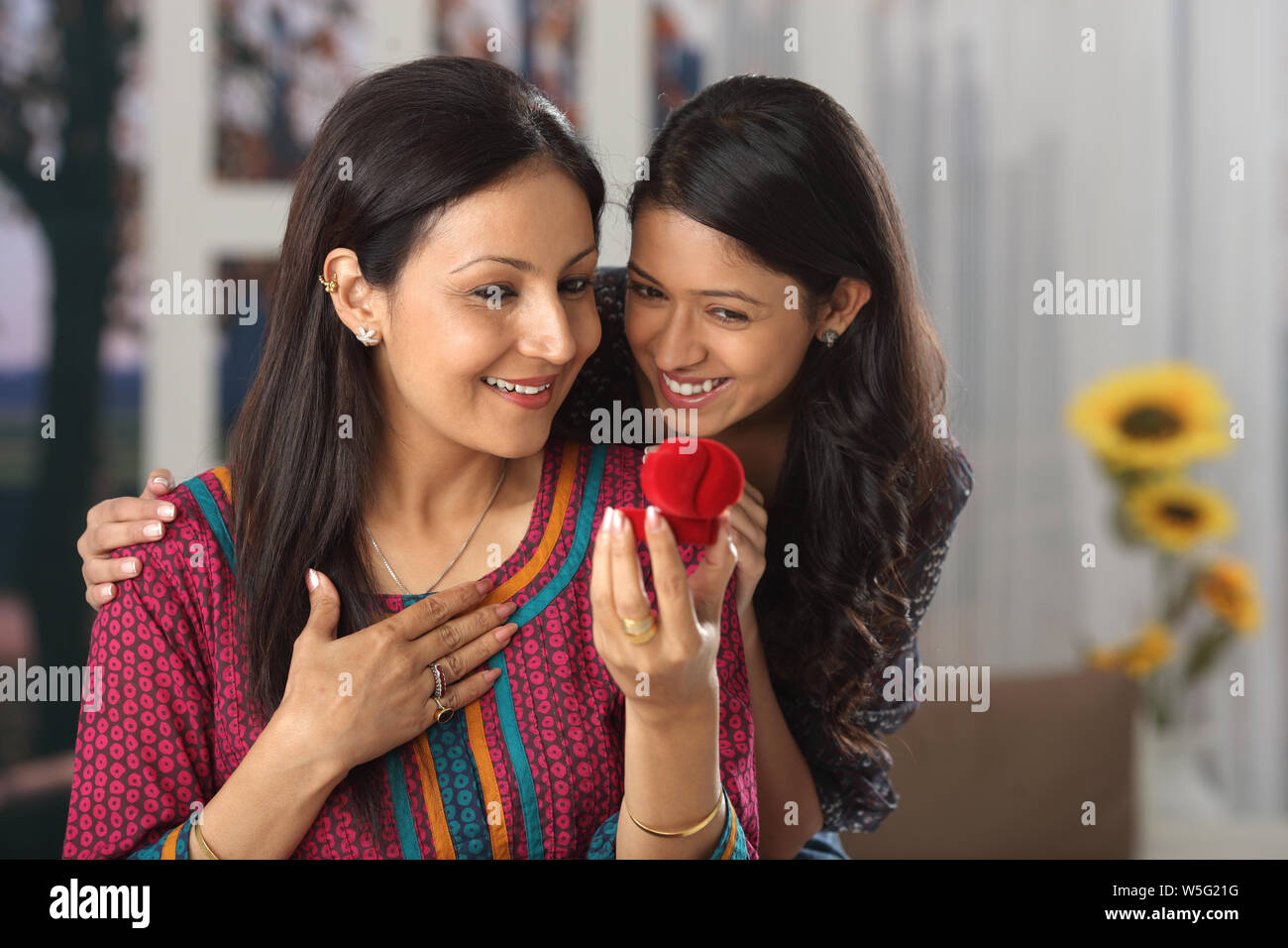 Girl giving surprise gift to her mother and smiling Stock Photo - Alamy