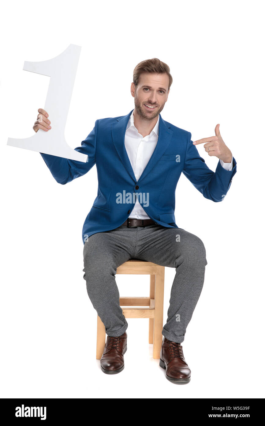 Young casual guy holding and pointing to a number one while wearing a ...