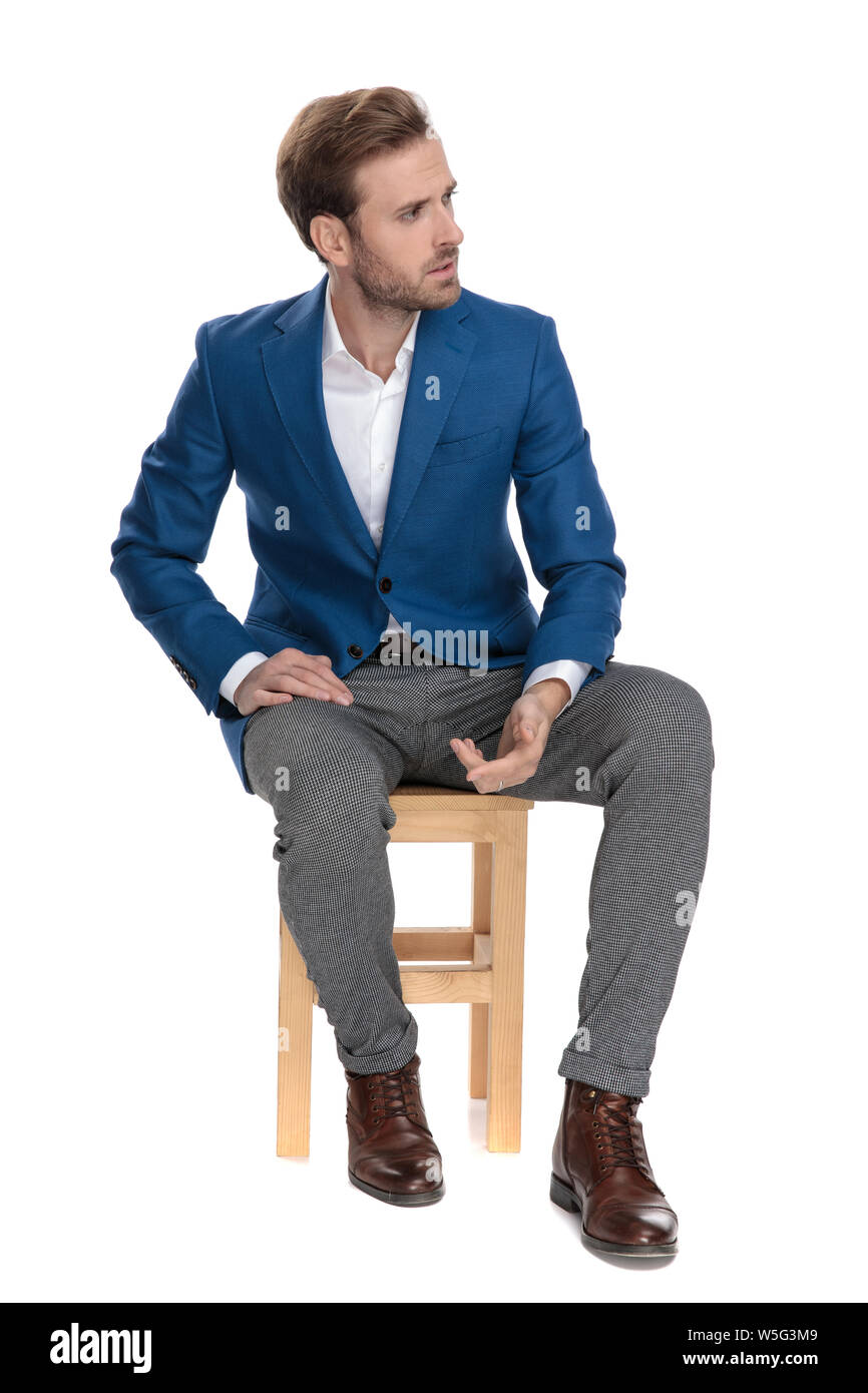 Upset casual man sitting and leaning on his leg while looking to the ...