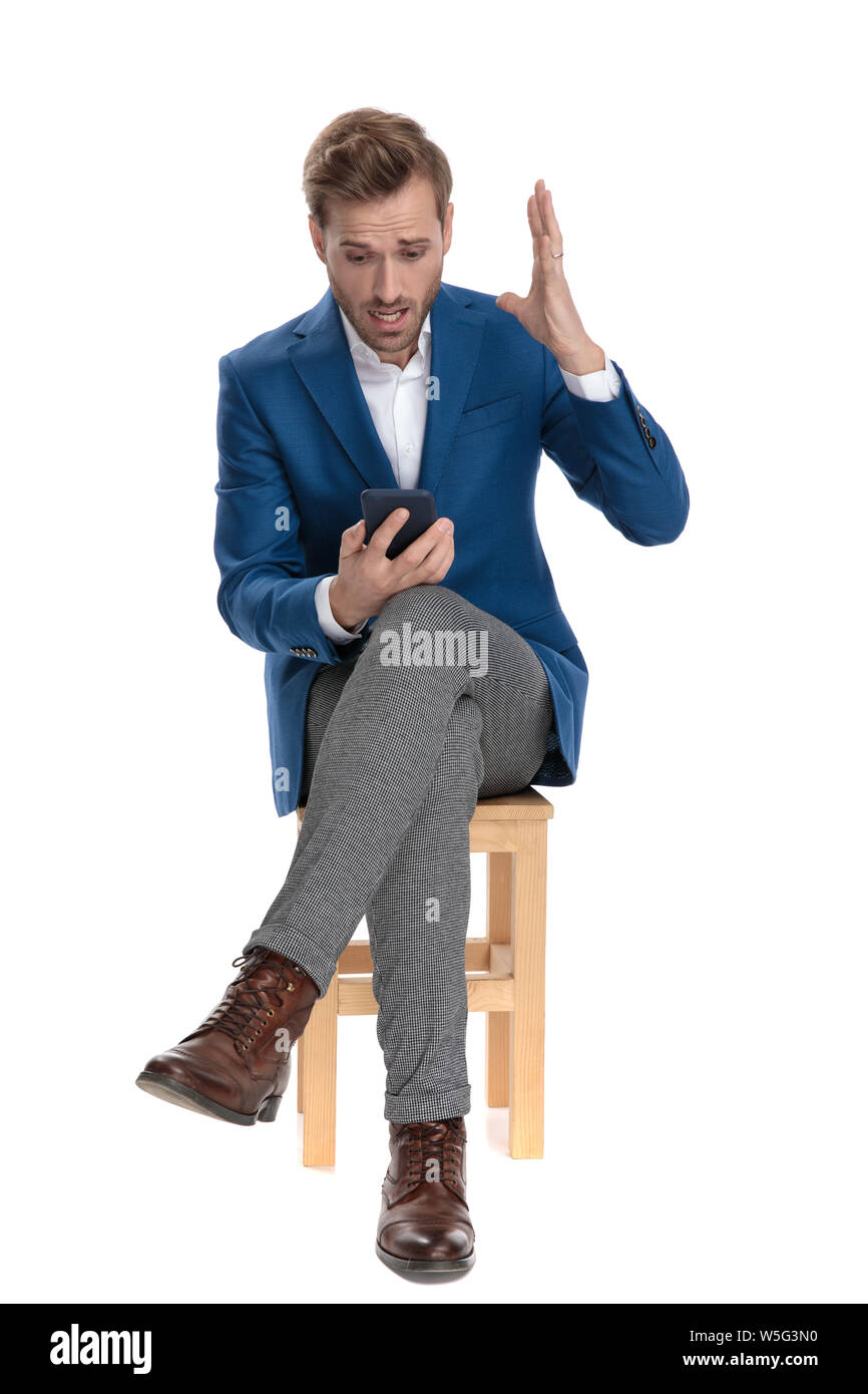 Amazed casual guy looking to his phone and screaming while wearing a ...