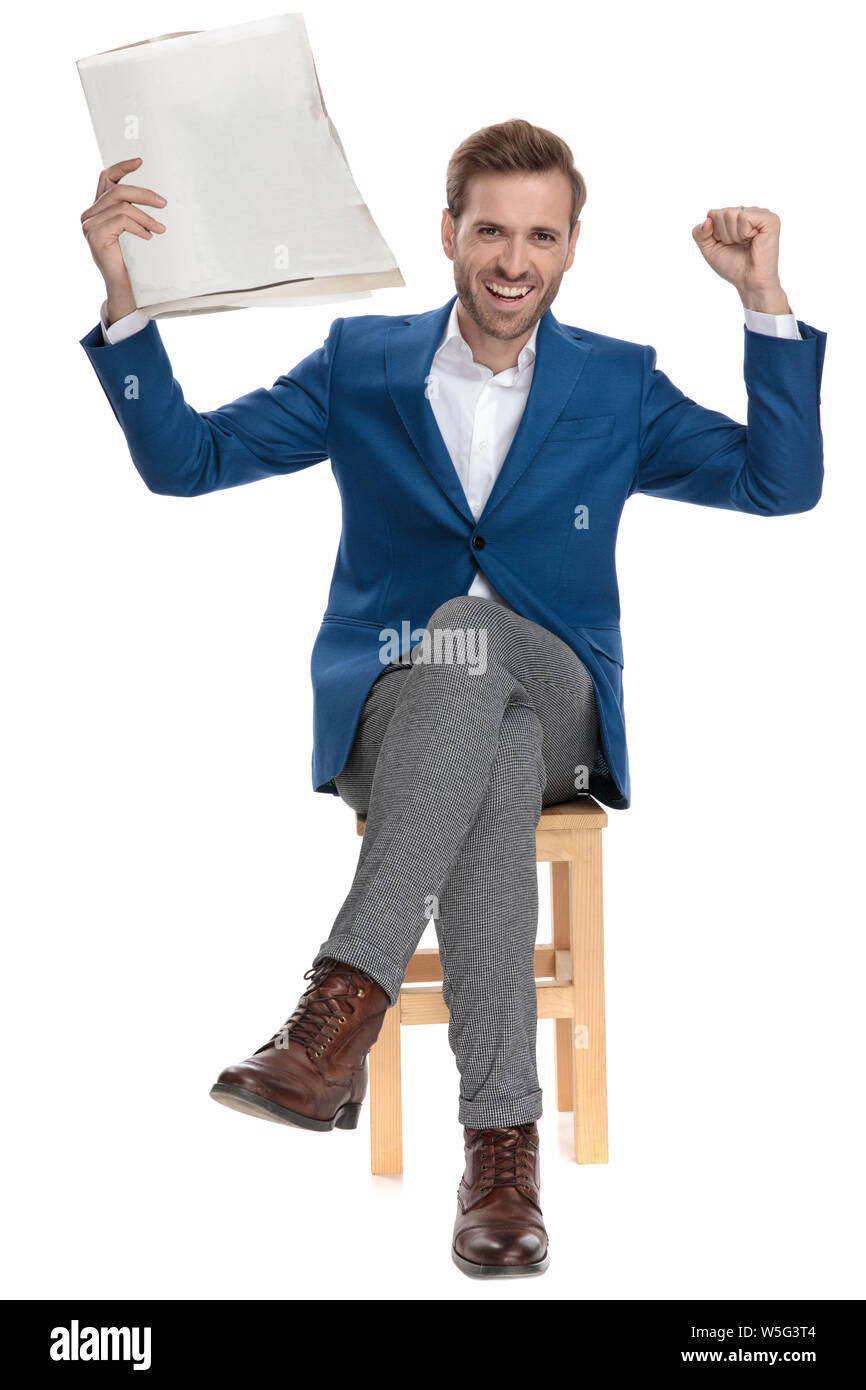 Cheerful casual man celebrating with a newspaper in his hand and arms ...