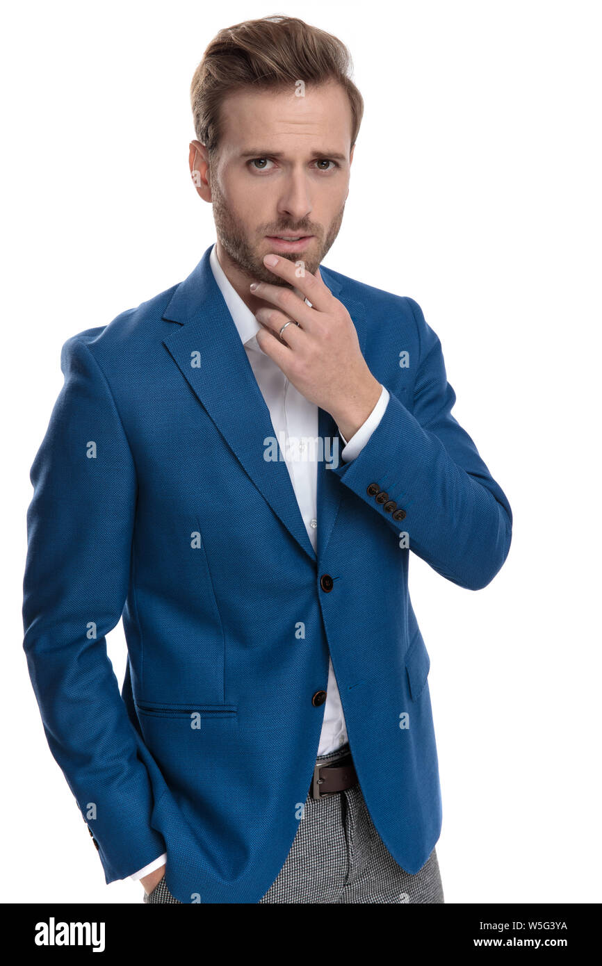 Nervous casual man holding his hand on his chin and in his pocket while ...